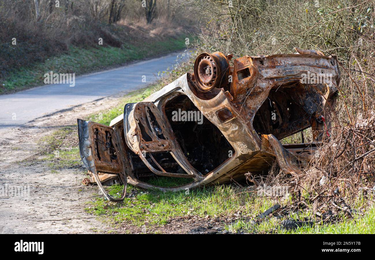 Wrecked car turned upside down on the side of the road after being burned in a crash accident ...