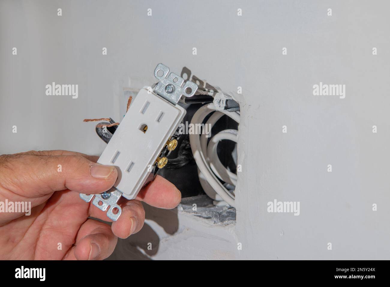 Electrician tries on the size of the hole in the wall to install the ...