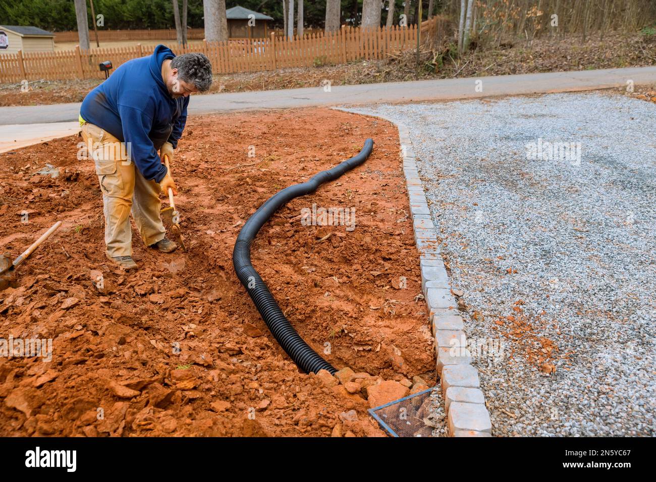 While heavy rainfall is occurring worker digs trench for laying ...