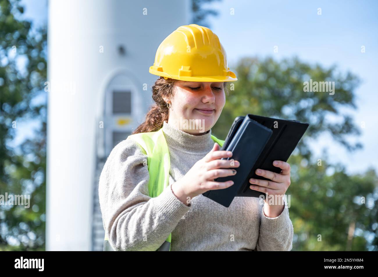 Engineer woman with yellow helmet and brown curly hair smiling while ...