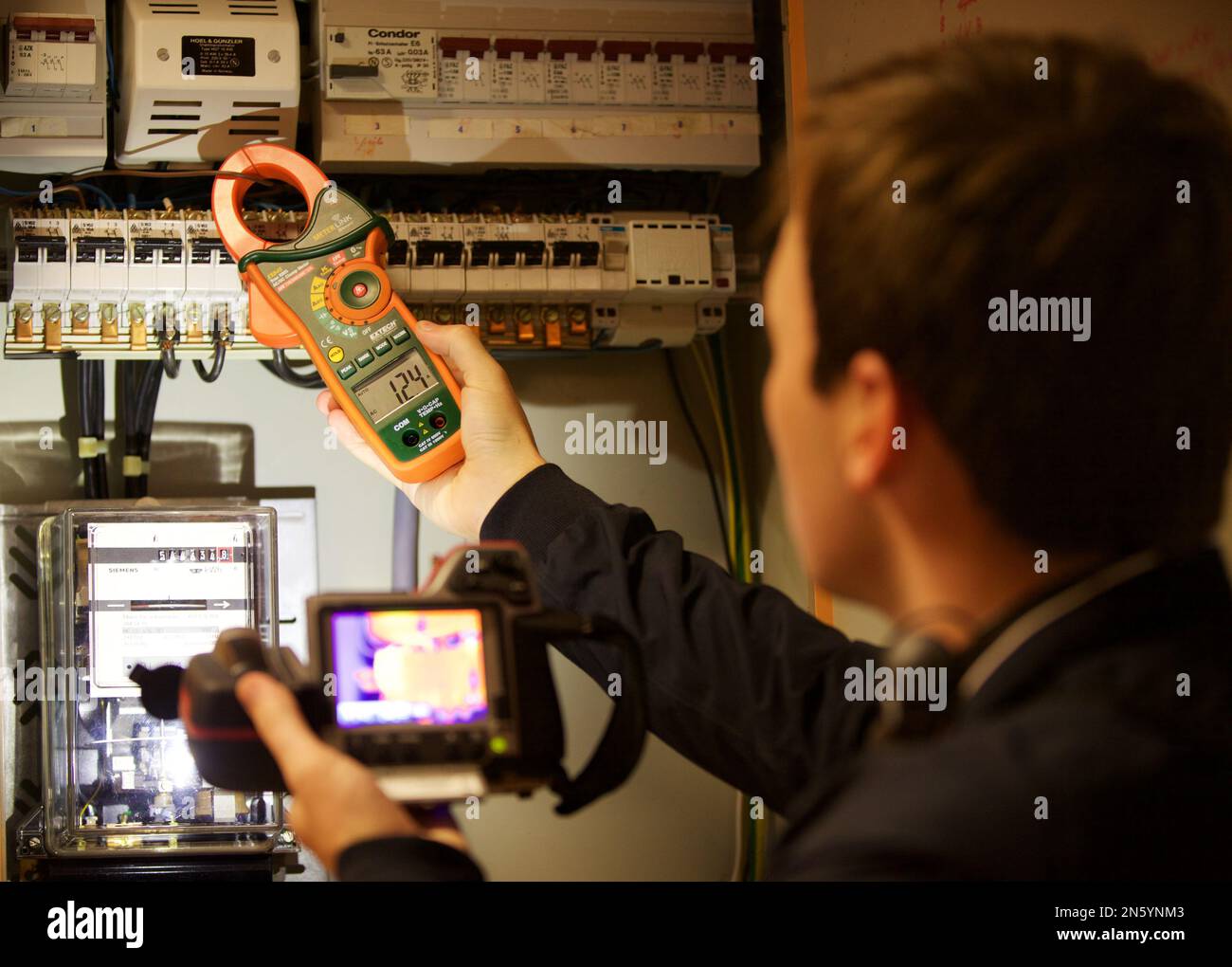 A man with thermal imaging camera checking electric installation with ...