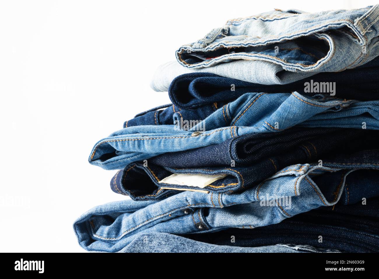 Diverse folded jeans lying in stack with copy space on white background ...