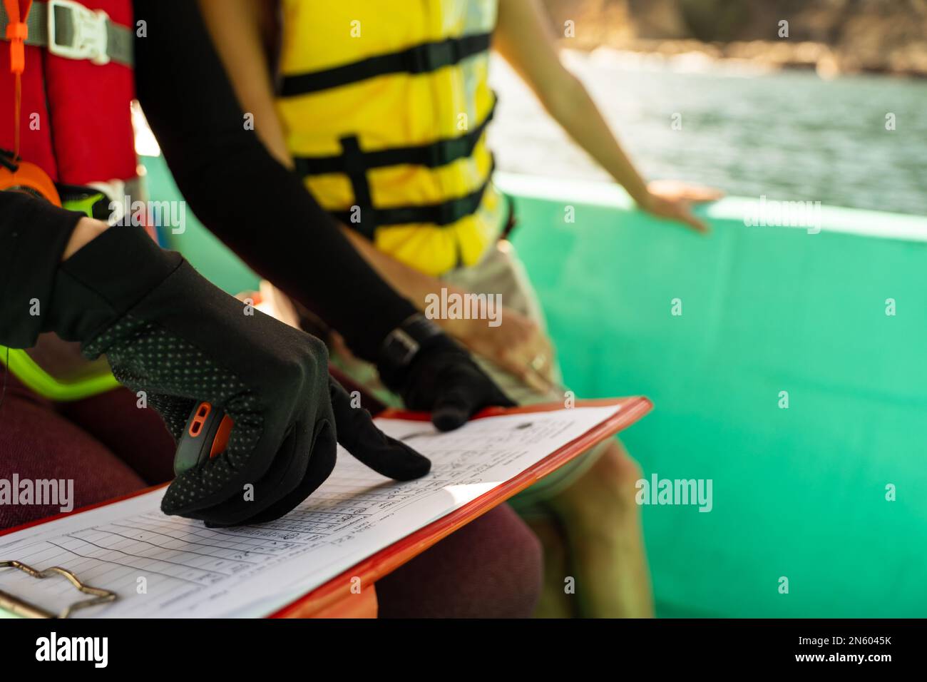 Finger of a marine biologist pointing to a paper with data on a boat ...
