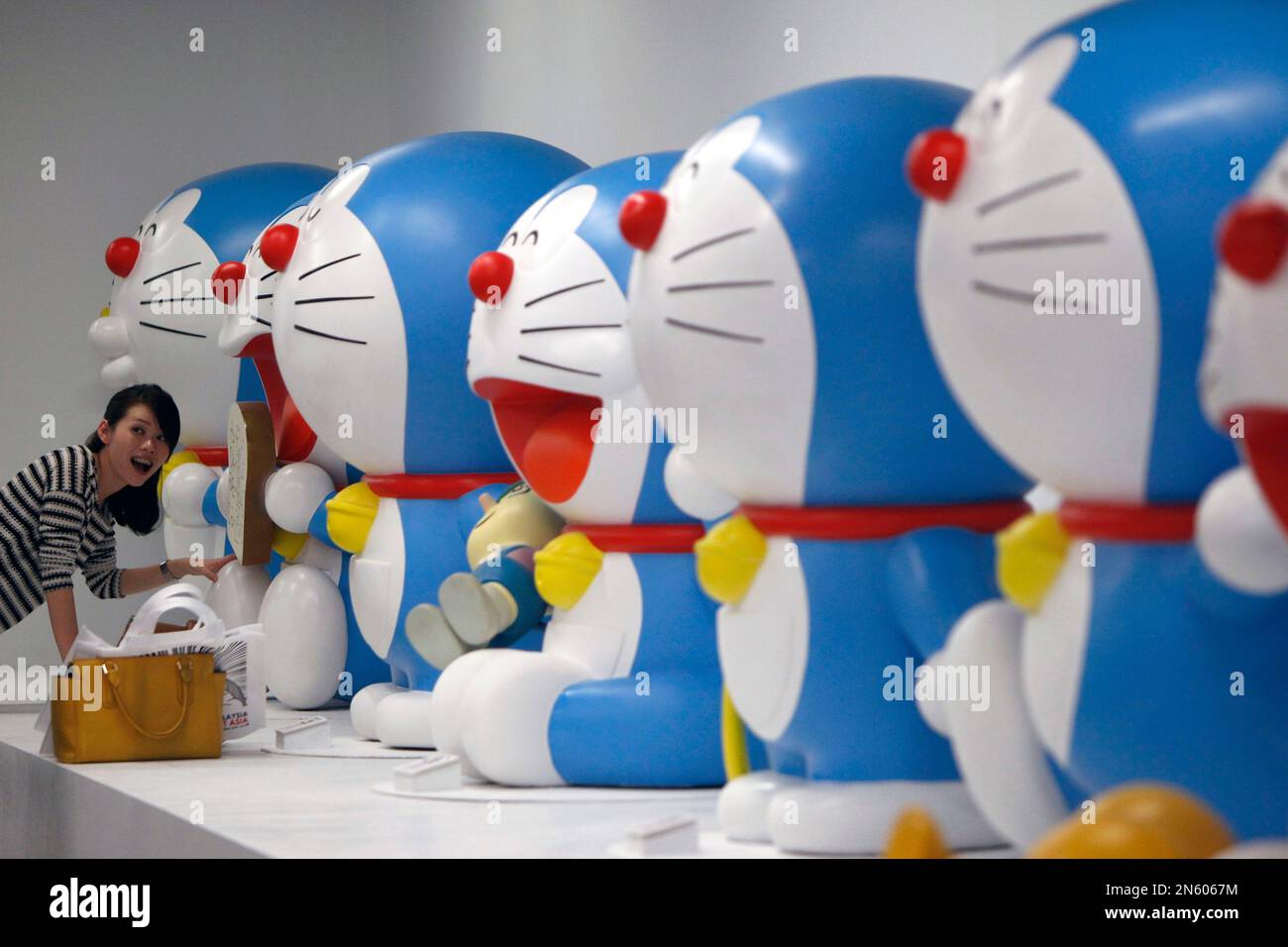 A visitor poses for a photo with models of Doraemon, one of Japan's ...