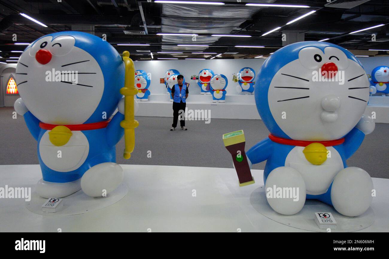 A worker stands among models of Doraemon, one of Japan's most popular ...