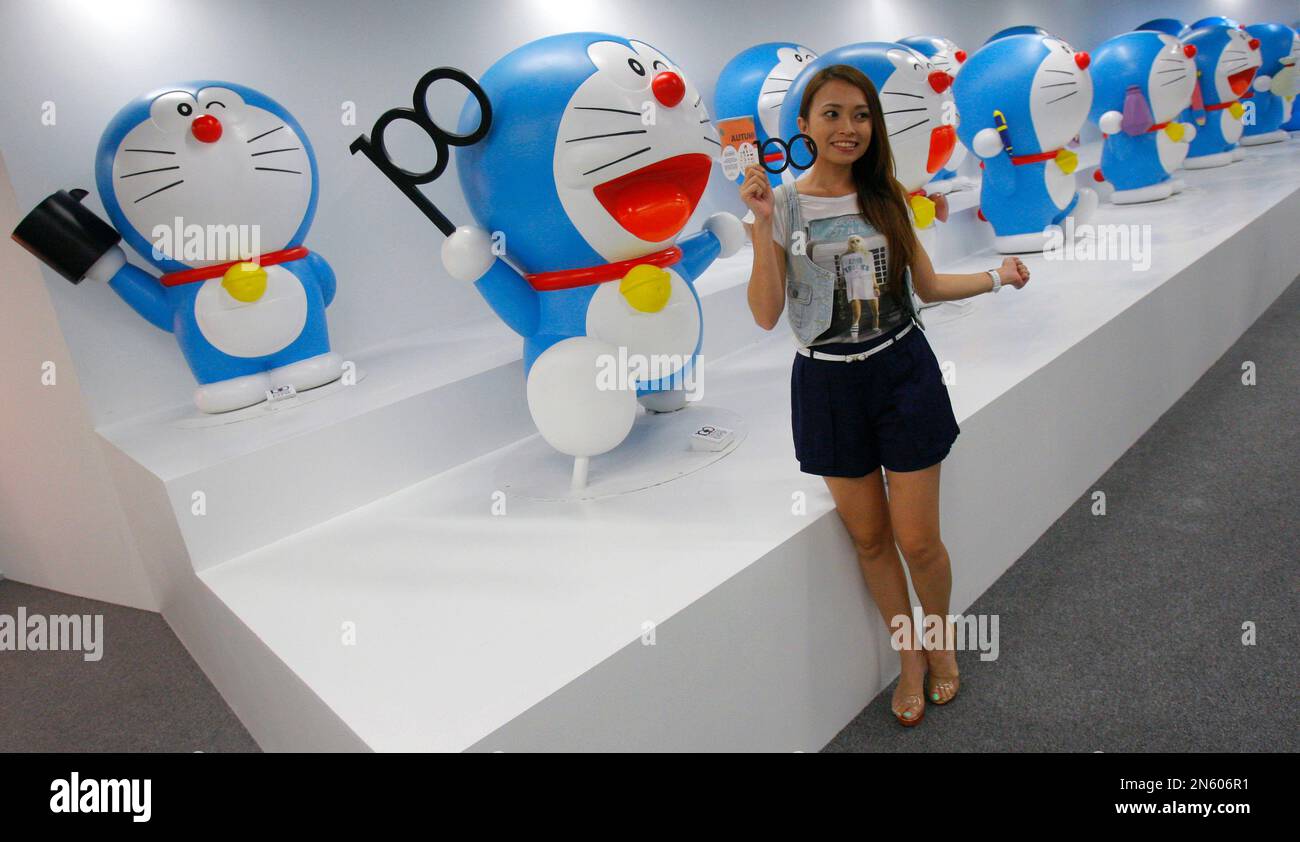 A visitor poses for a photo with models of Doraemon, one of Japan's ...