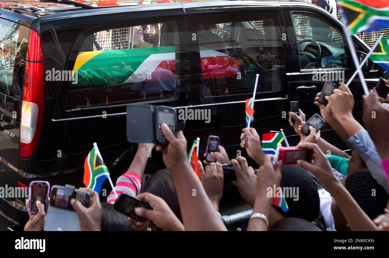 Mourners take photographs using their mobile phones as the casket of ...