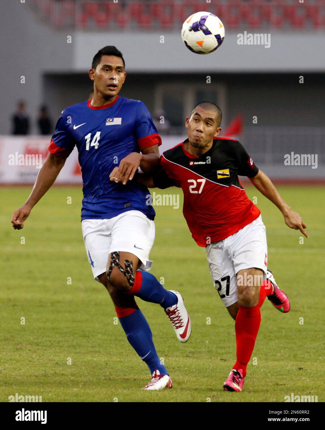 Azri Zahari of Brunei, red, vies the ball with Izzaq Faris Ramlan of ...