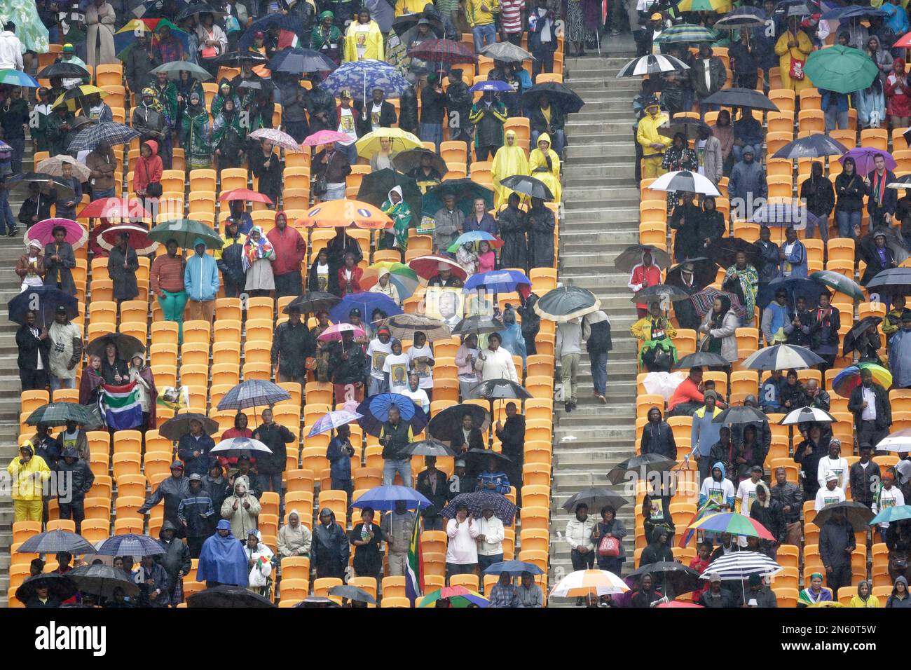 People shelter under umbrellas during the funeral service for former ...