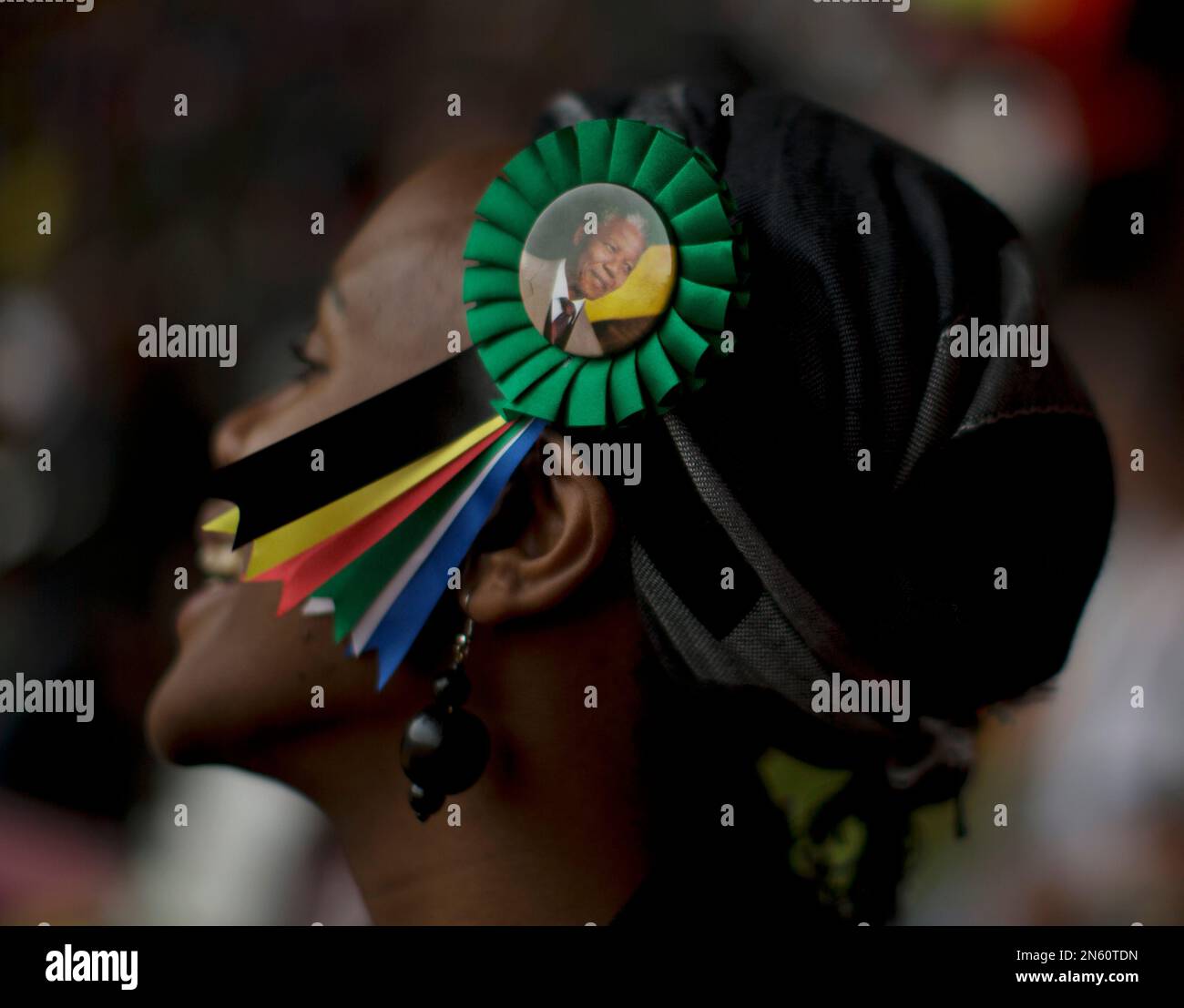 A mourner wears a Nelson Mandela button as she waits for the memorial ...