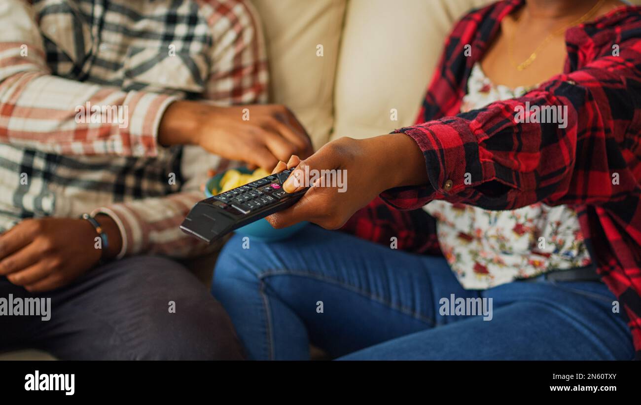 Woman changing tv channels to find film with remote control, searching ...