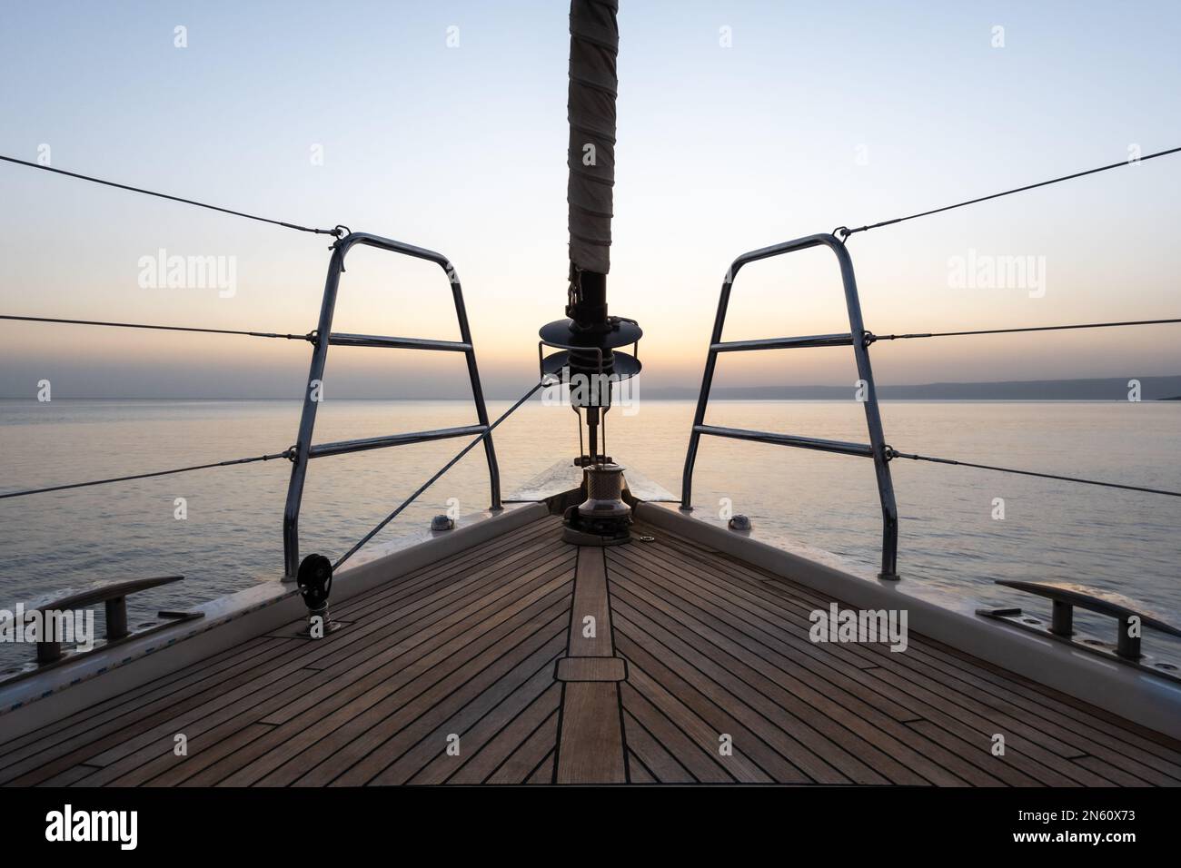 The bow of a sailing yacht in pointing into the sunset on a calm sea in ...