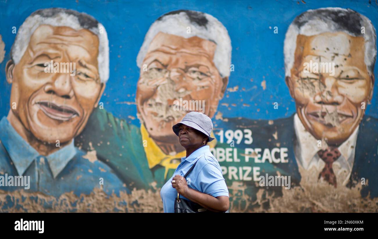 A woman walks past a mural depicting Nelson Mandela during different ...