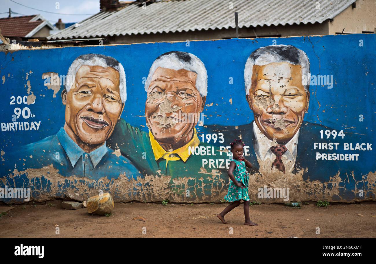 A girl walks past a mural depicting Nelson Mandela during different ...