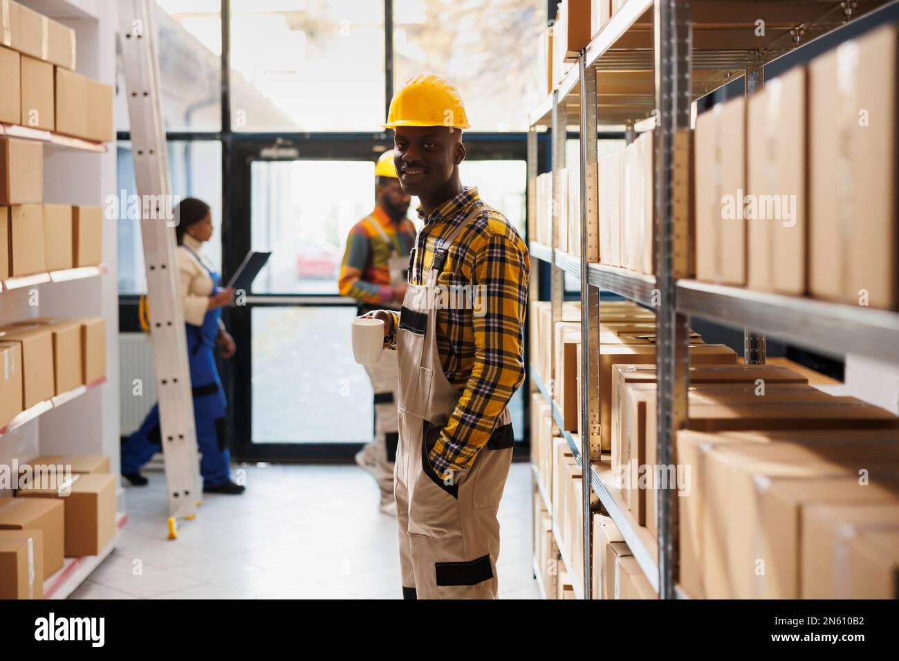 African american smiling warehouse worker standing near cardboard boxes ...