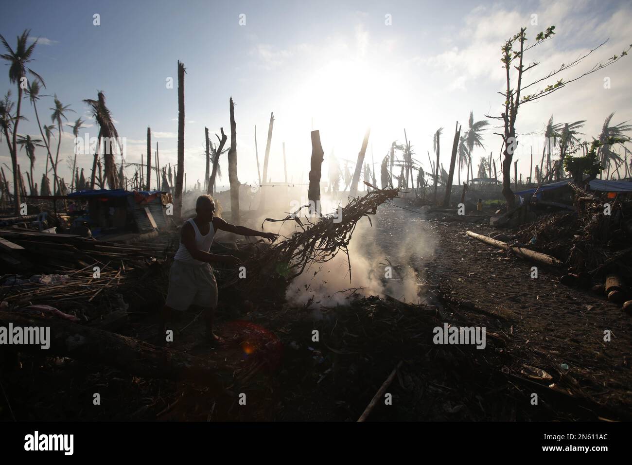 Typhoon survivor Manuel Lazada, 65, burns debris from Typhoon Haiyan ...