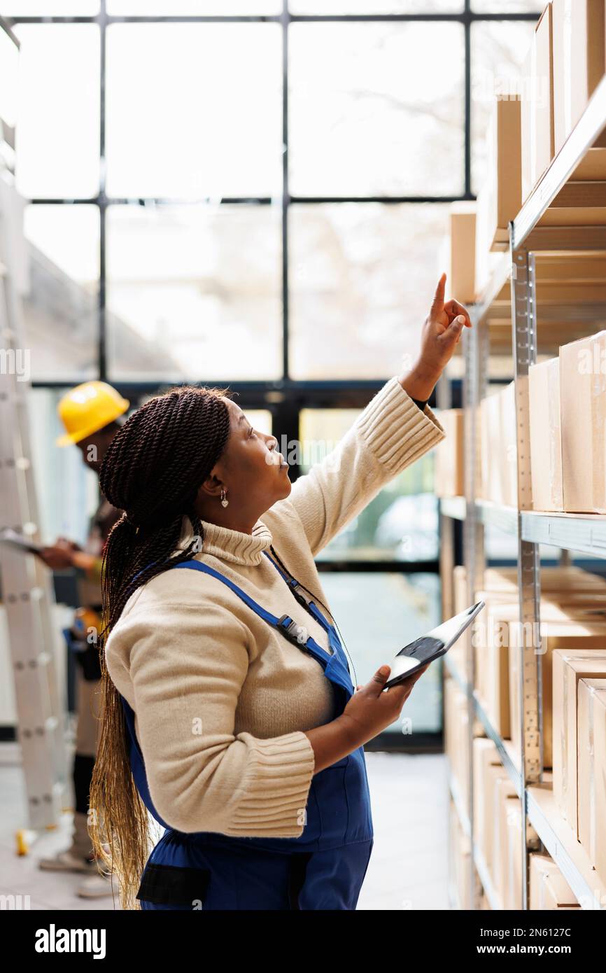 Warehouse worker reaching for parcel at cardboard boxes shelf and doing ...