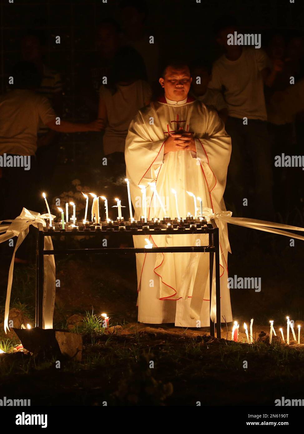 A Filipino Catholic priest offers prayers at a mass grave during ...