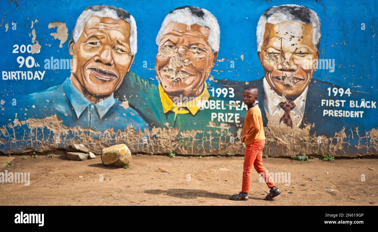 A boy walks past a mural depicting Nelson Mandela during different ...