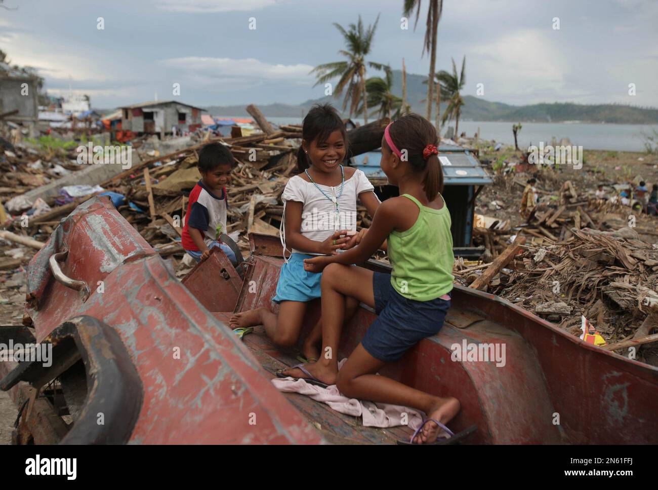 Girl survivors play on top of a damaged vehicle at typhoon ravaged ...