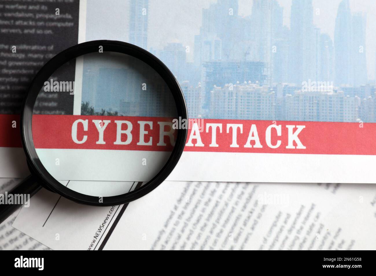 Newspaper with headline CYBER ATTACK and magnifying glass, top view ...