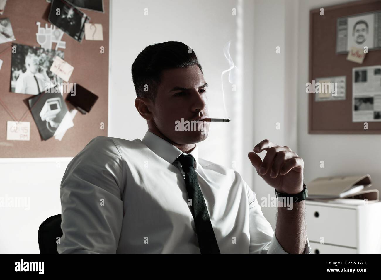 Professional detective smoking cigarette in his office Stock Photo - Alamy