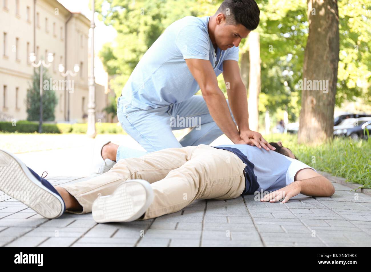 Passerby performing CPR on unconscious young man outdoors. First aid ... Passerby performing CPR on unconscious young man outdoors. First aid ...