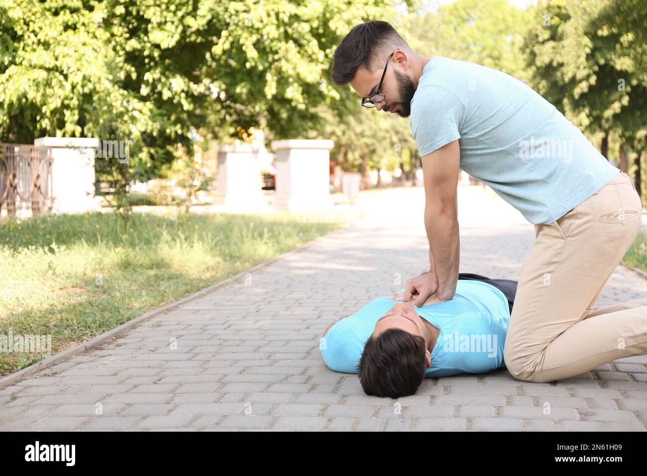 Passerby performing CPR on unconscious man in park. First aid Stock ...