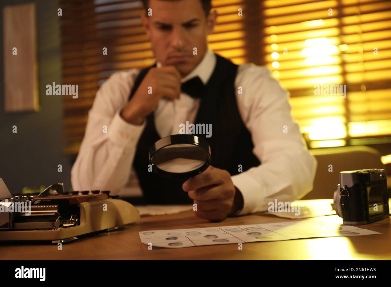 Old fashioned detective with magnifying glass working at table in ...