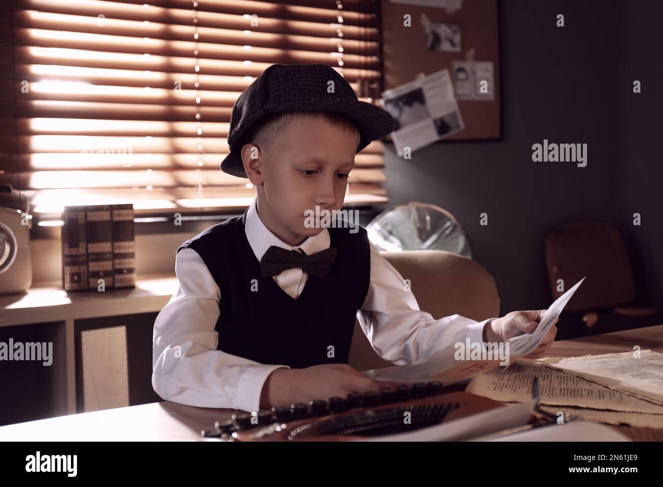 Cute little detective with fingerprints card at table in office Stock ...