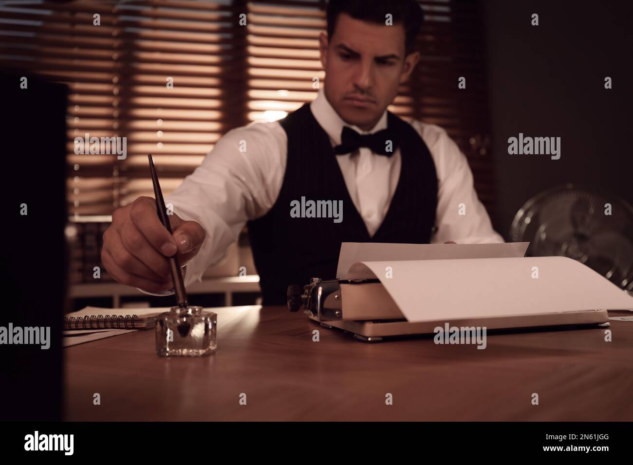 Old fashioned detective working at table in office, focus on hand with ...
