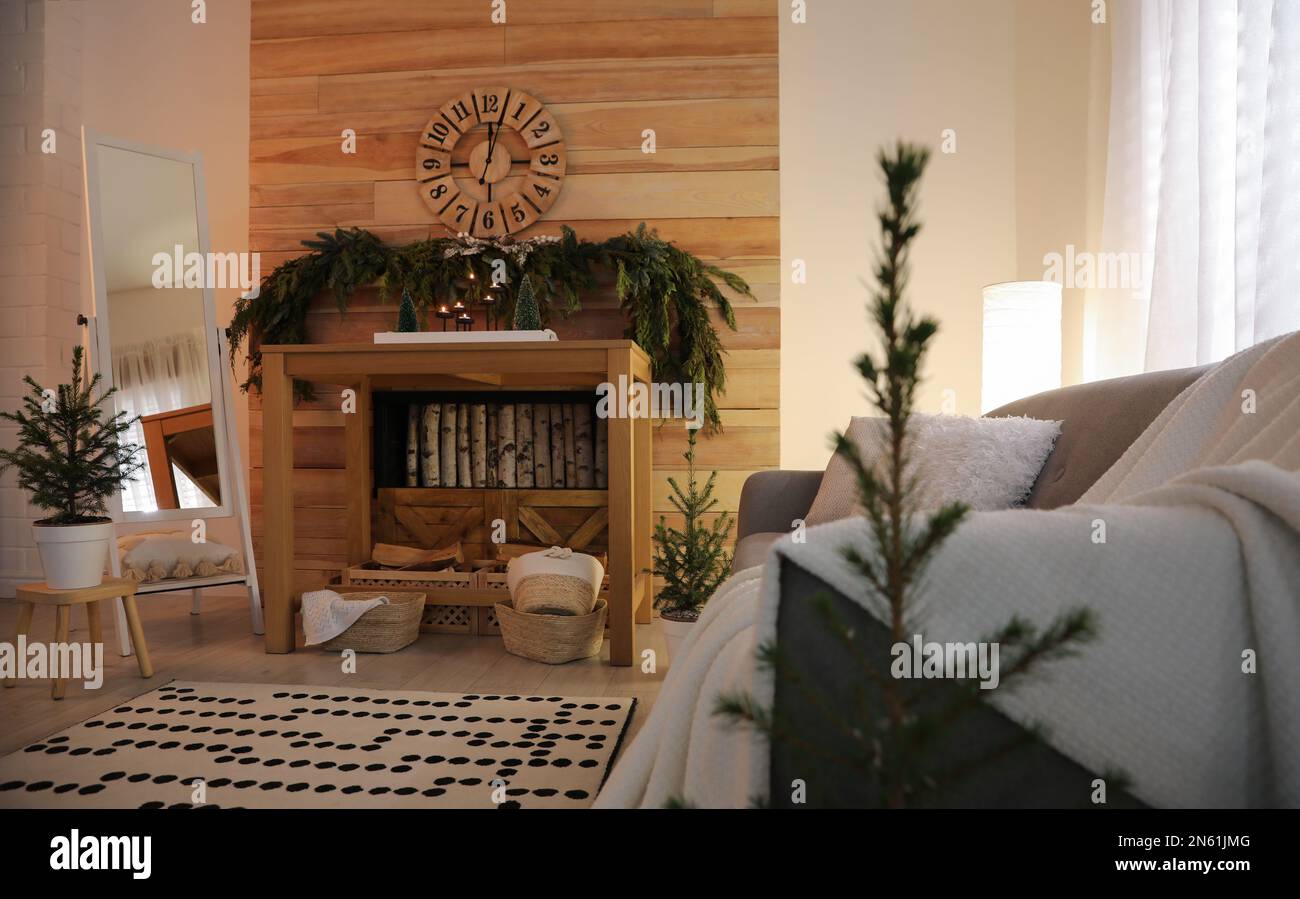 Cozy room interior with console table and conifer garland near wooden ...