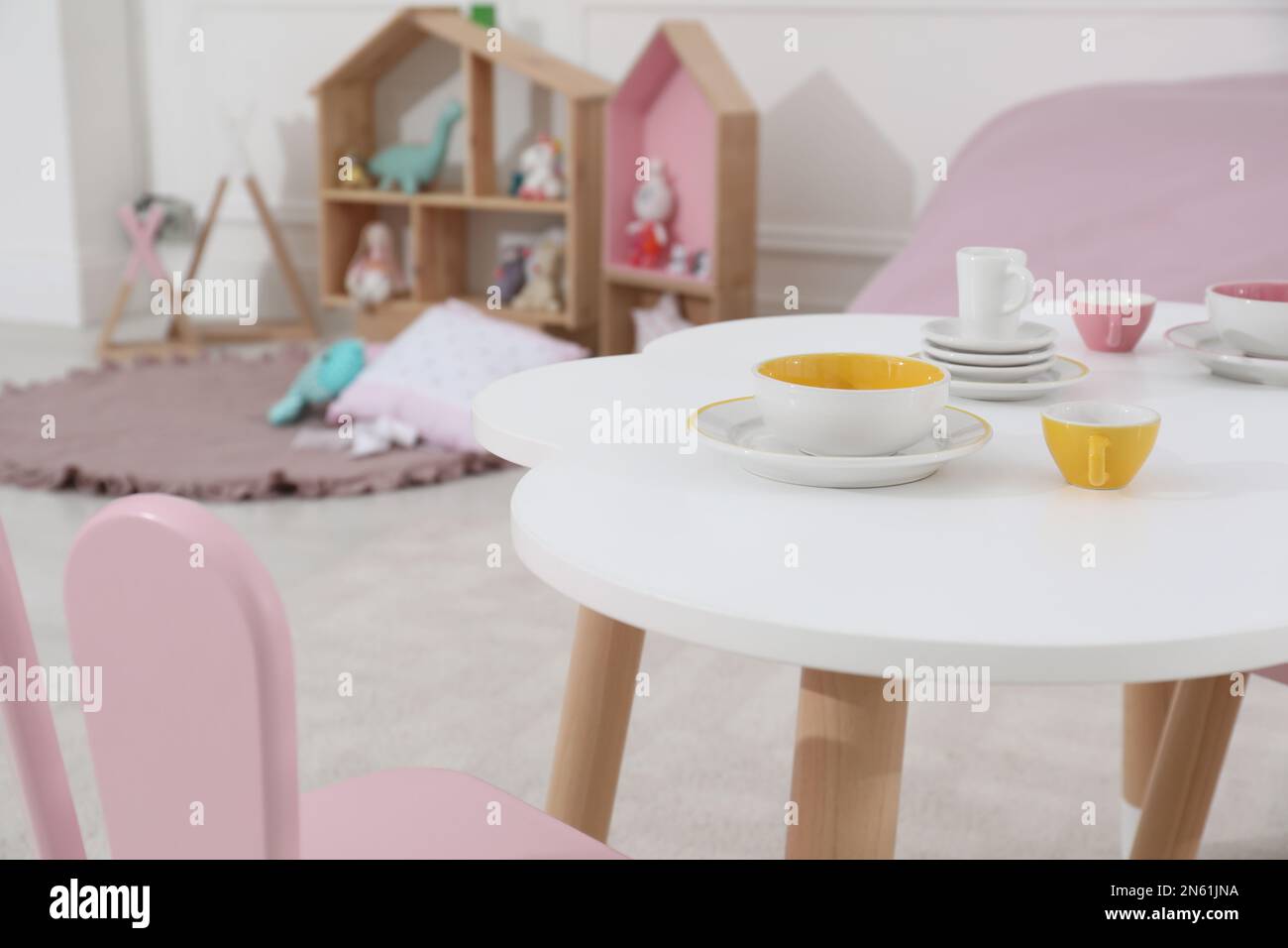 Toy tableware on white table in playroom. Interior design Stock Photo ...