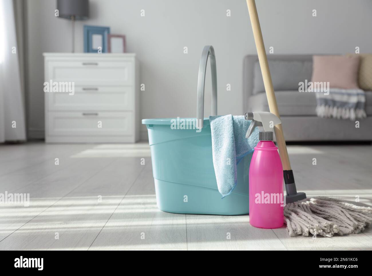 Bucket, mop and bottle of cleaning product on floor indoors. Space for ...