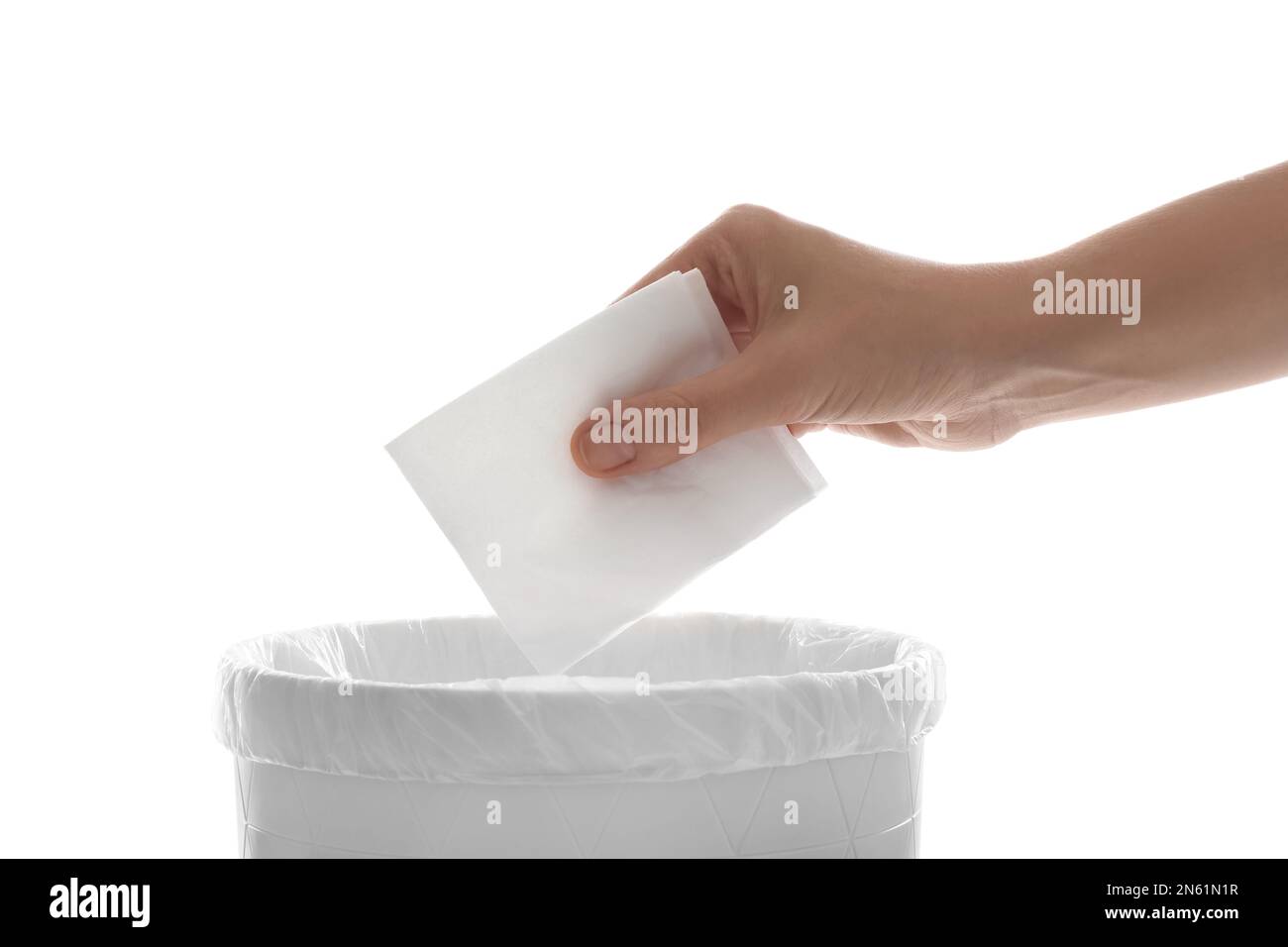 Woman putting paper tissue into trash bin on white background, closeup ...