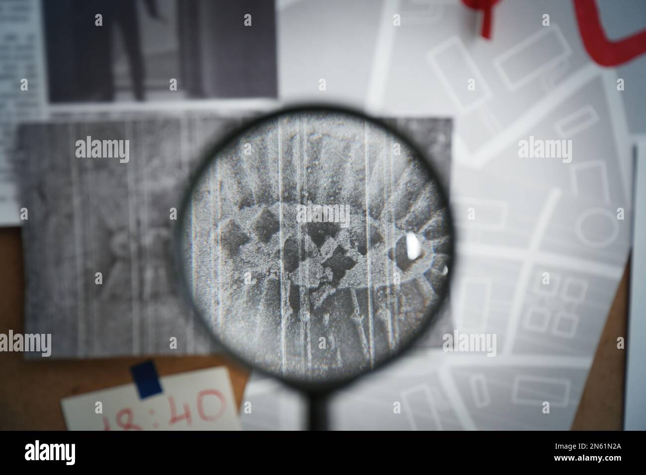 Looking through magnifying glass at photo of footprint on detective ...