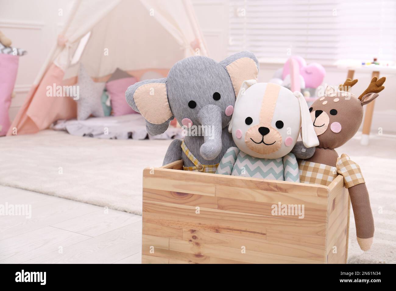 Wooden crate with cute toys in stylish playroom, space for text ...