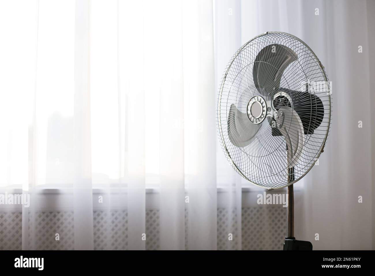 Modern electric fan near window indoors. Space for text Stock Photo - Alamy