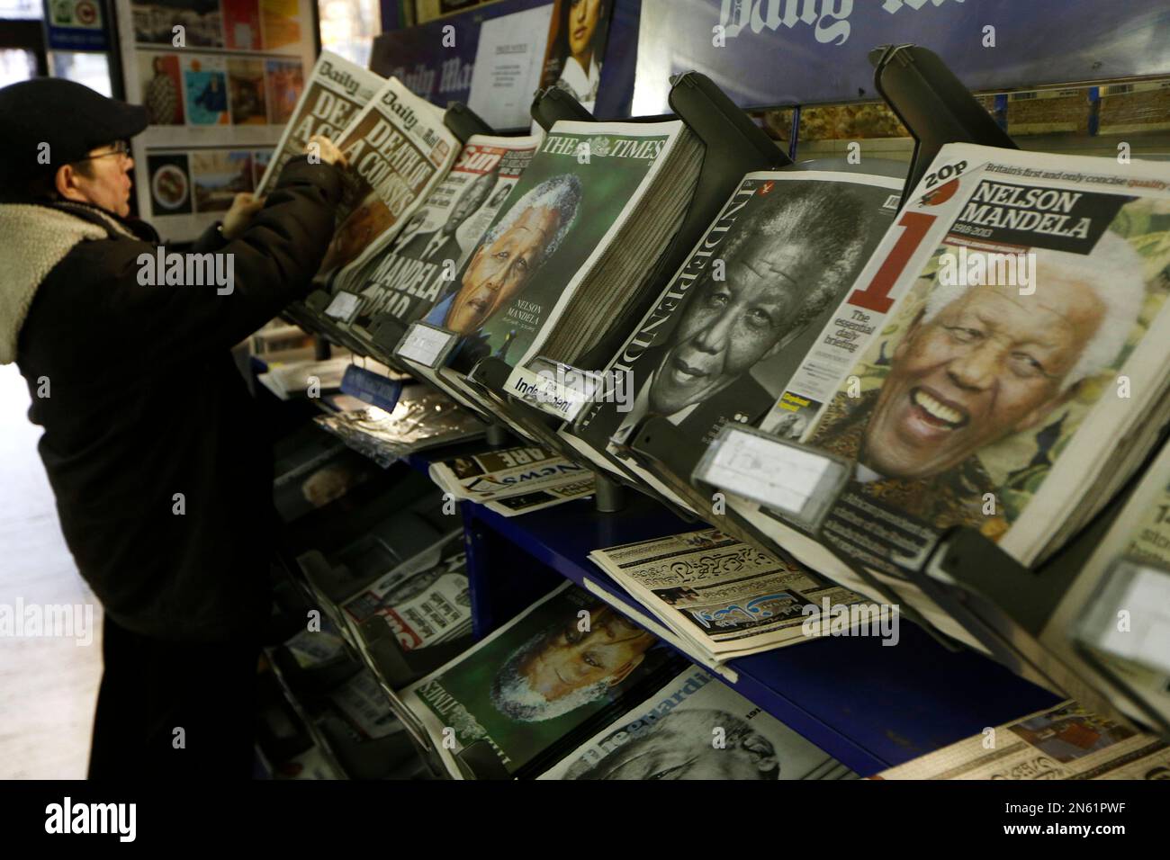 A man takes a newspaper from a display rack of newspapers with pictures ...