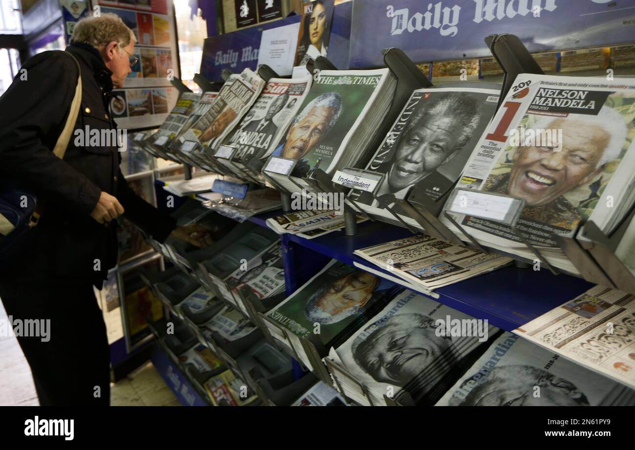A man takes a newspaper from a display rack of newspapers with pictures ...