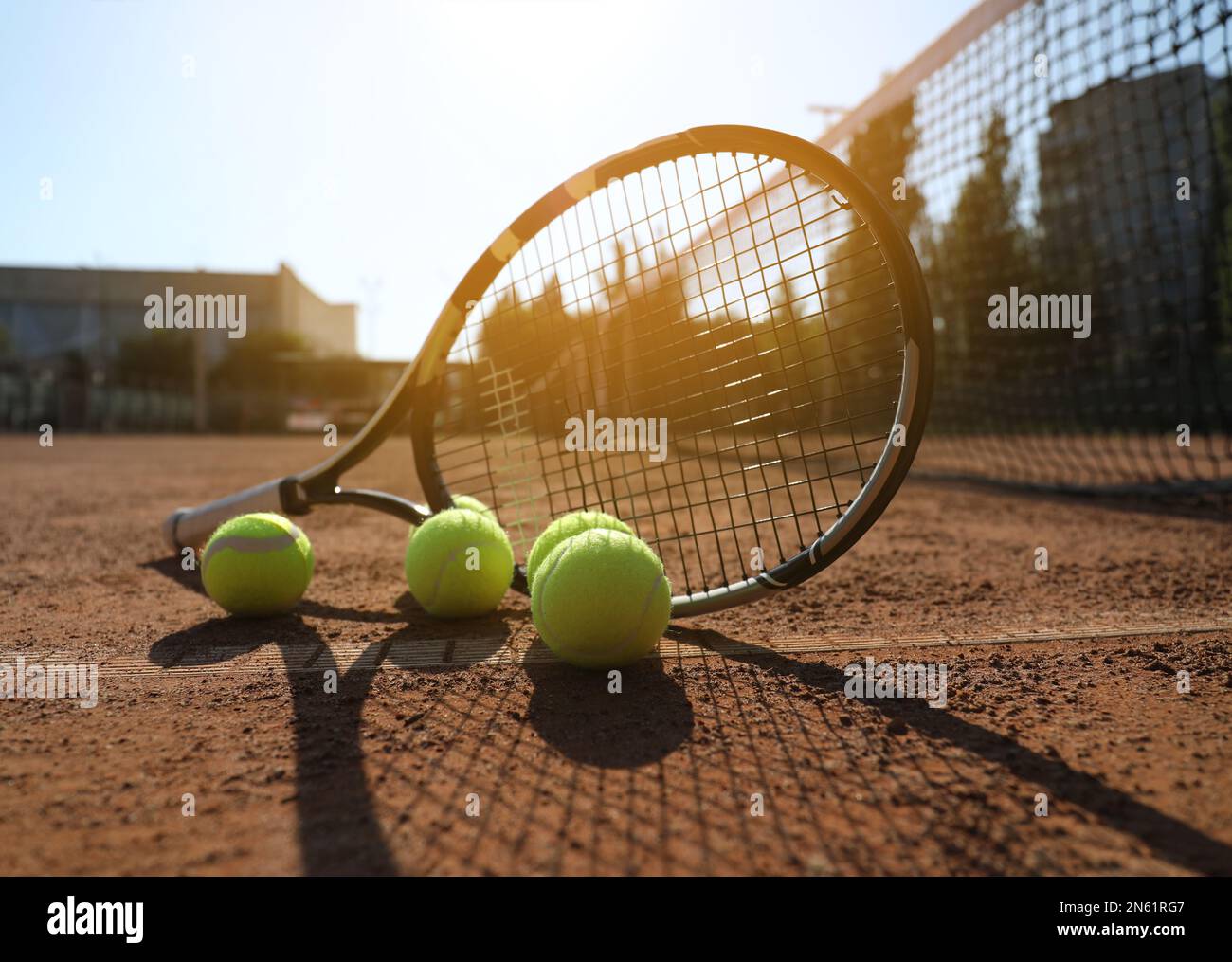 Tennis balls and racket on clay court Stock Photo - Alamy