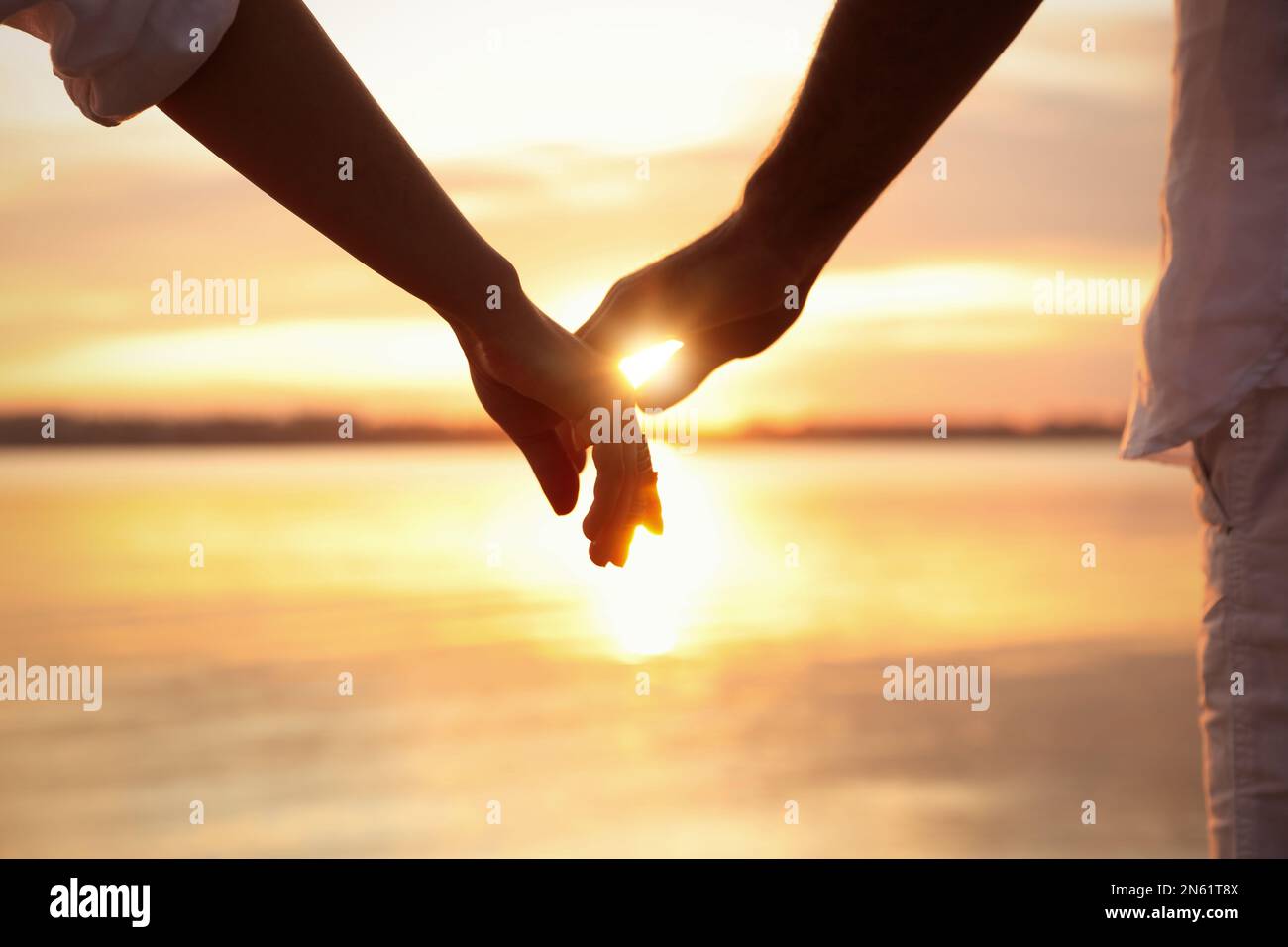 Man and woman reaching hands to each other at sunset, closeup. Nature ...