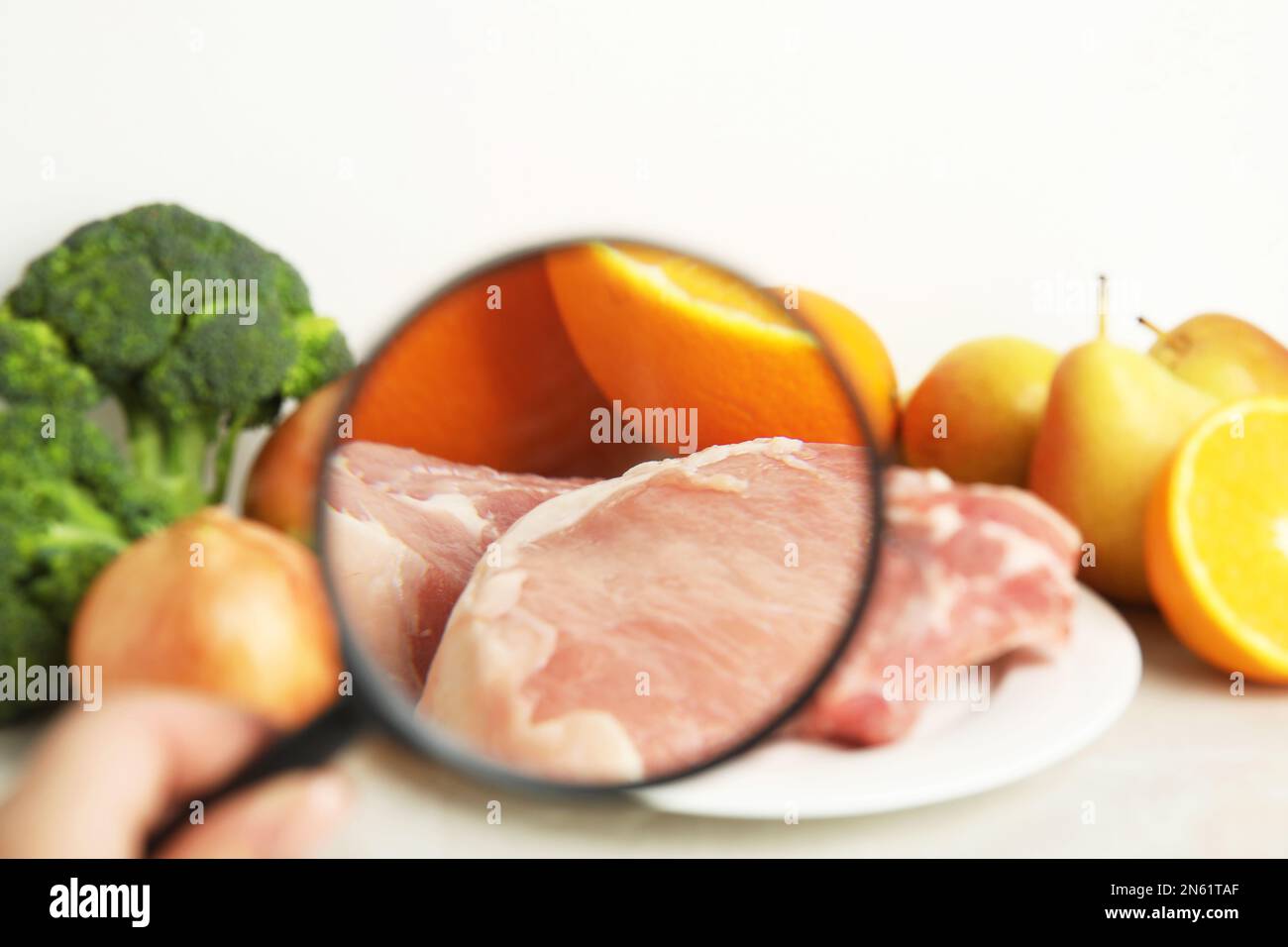 Woman with magnifying glass exploring raw meat and fruits, closeup ...