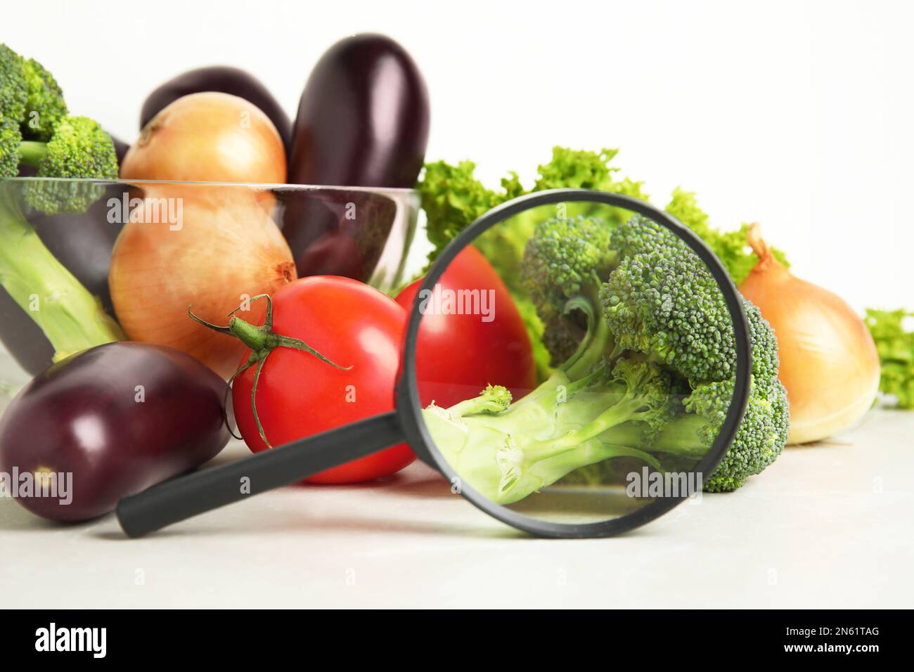 Different fresh vegetables and magnifying glass on table, closeup ...