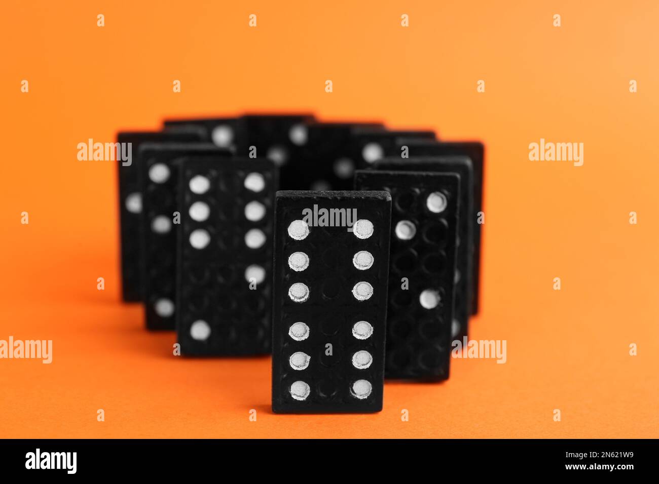 Black domino tiles with white pips on orange background Stock Photo - Alamy