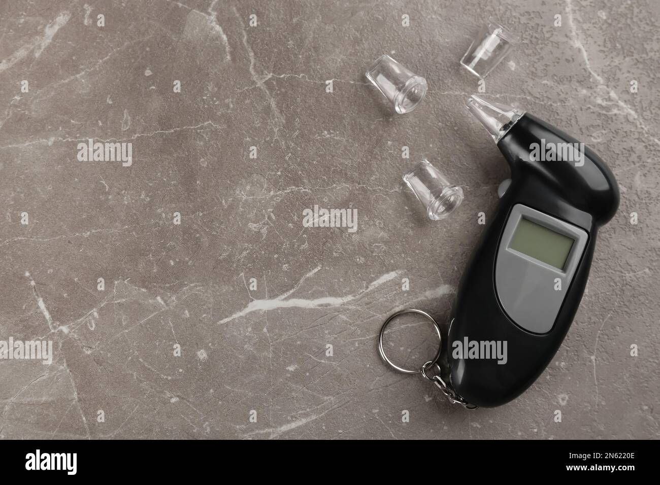 Modern breathalyzer with blank screen and mouthpieces on brown marble ...