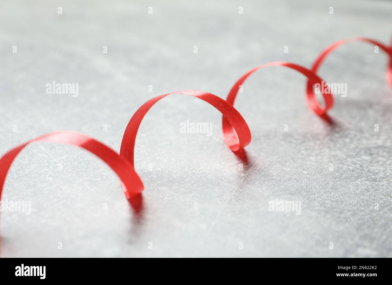 Shiny red serpentine streamer on grey background, closeup Stock Photo ...