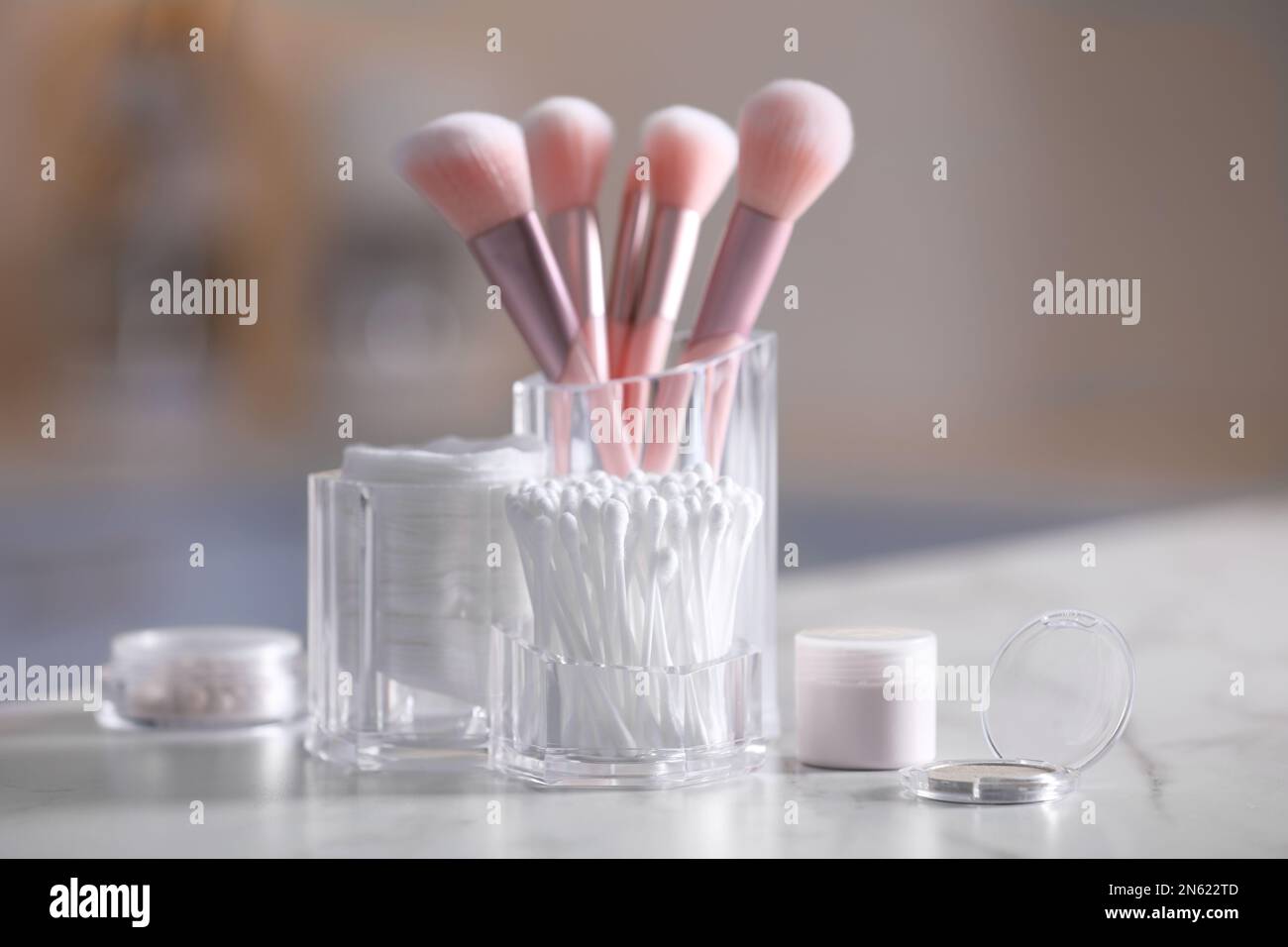 Cotton buds, pads and makeup brushes in transparent holders on light ...