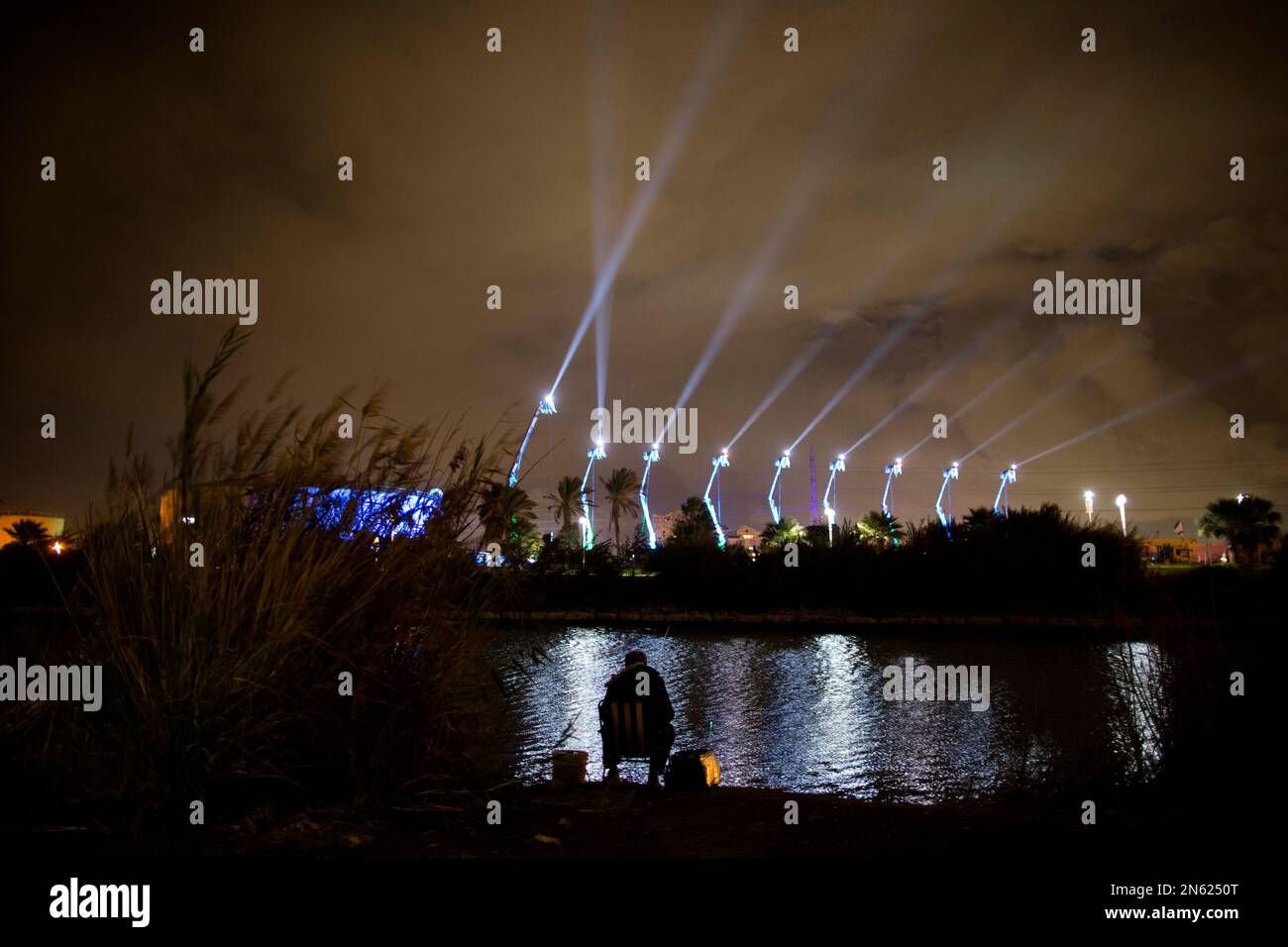 An Israeli fisherman casts his fishing rod to Hayarkon river, against a ...