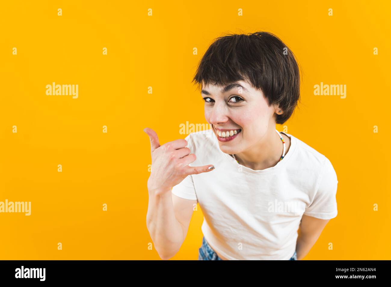 Studio portrait of funky short-haired girl doing Shaka sign to the ...